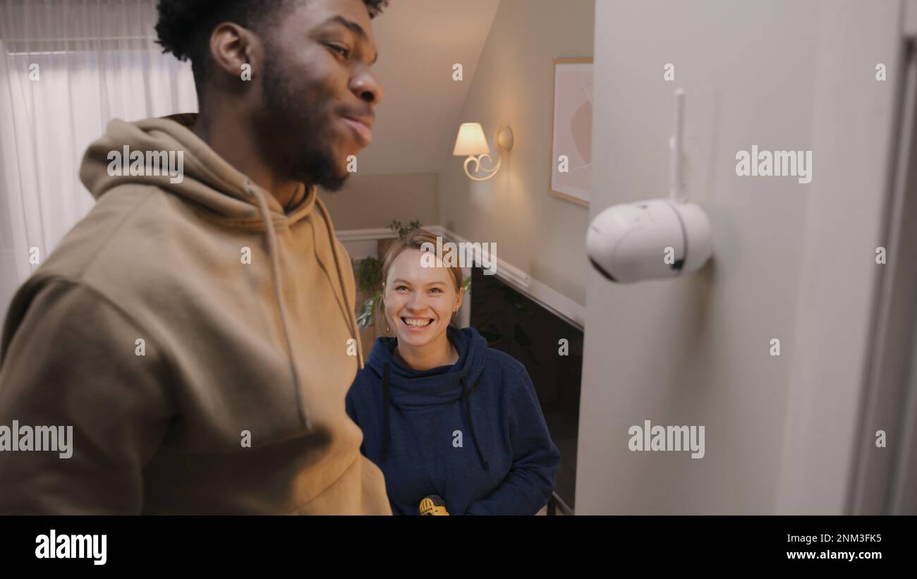 African American man connects security camera with wire and fastening ...