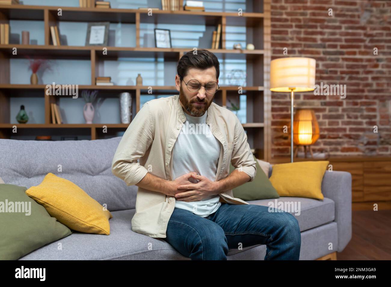 A young man feels severe stomach pain, spasms, poisoning, discomfort ...