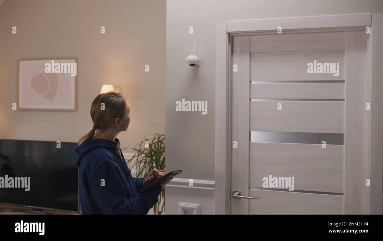 Caucasian woman completes installation of security camera. Woman sets ...