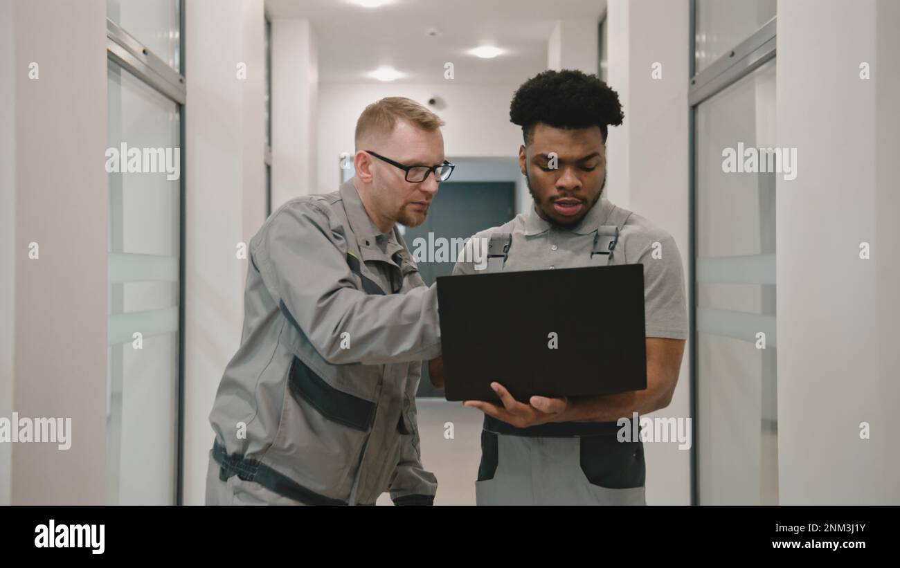 Two installers in uniform stand in corridor and discuss security ...