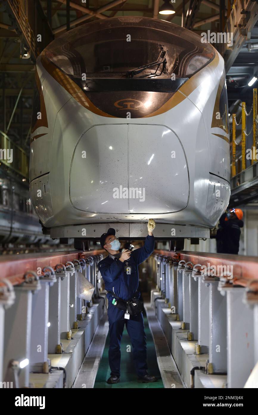 A worker inspects a Fuxing Hao high-speed train at a maintenance ...