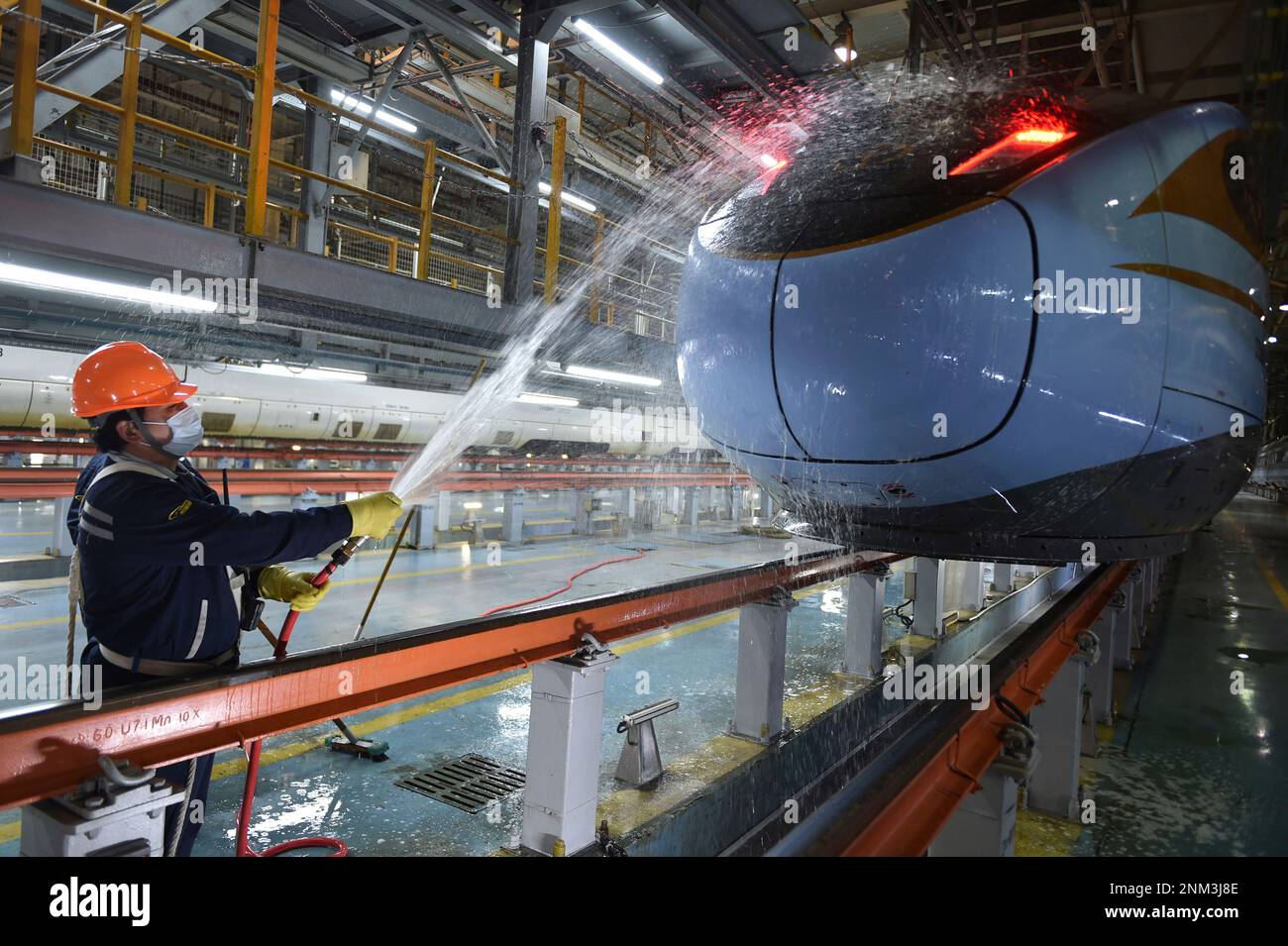 A worker cleans a Fuxing Hao high-speed train at a maintenance station ...