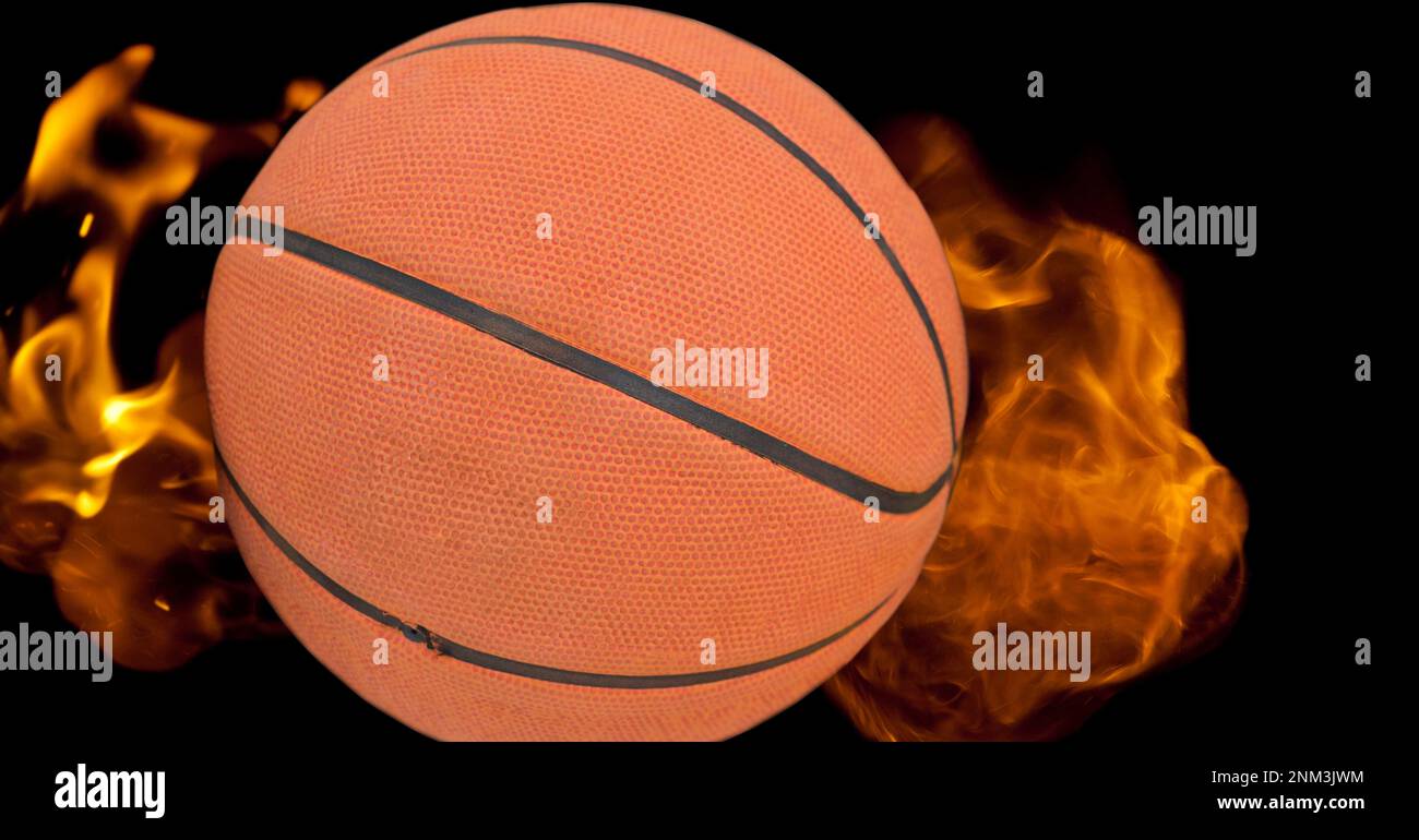 Composition of basketball ball surrounded by flames on black background ...