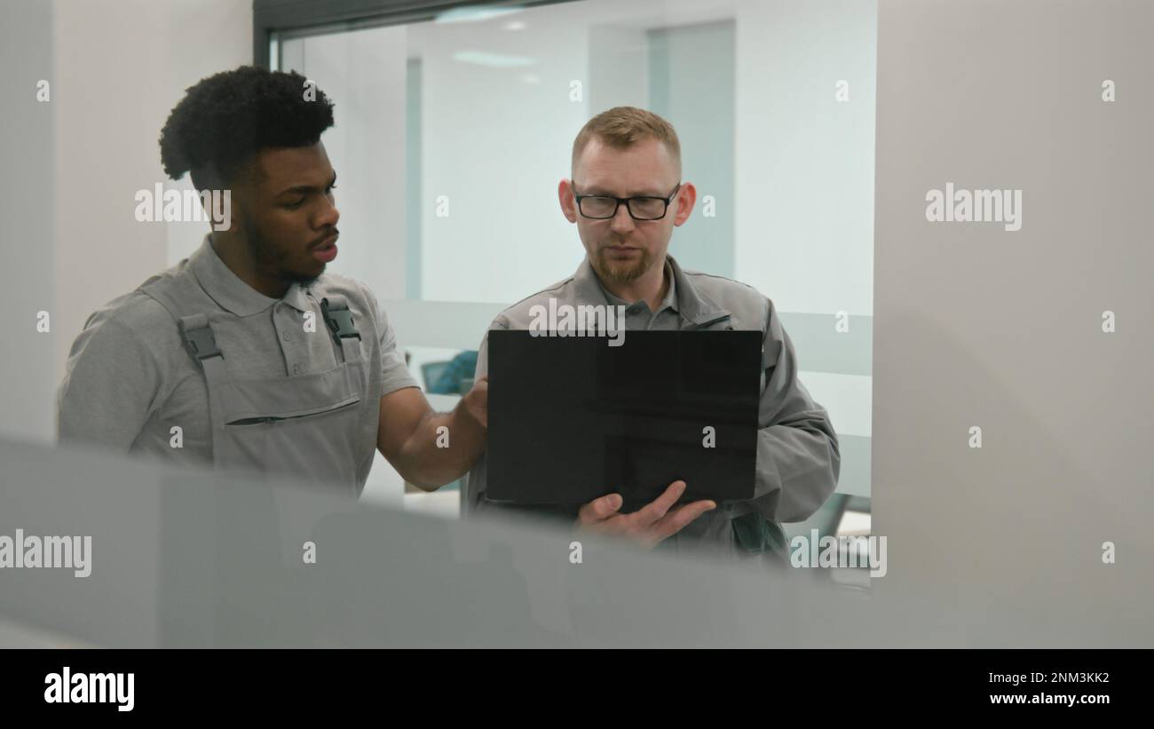 Two diverse installers in uniform sets up security cameras or Internet ...