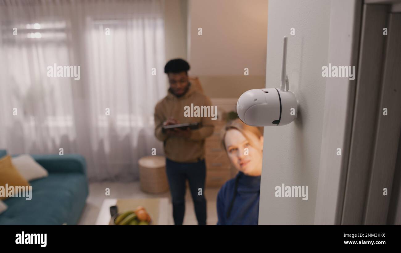Multi ethnic couple install and set up security camera. Woman moves to ...