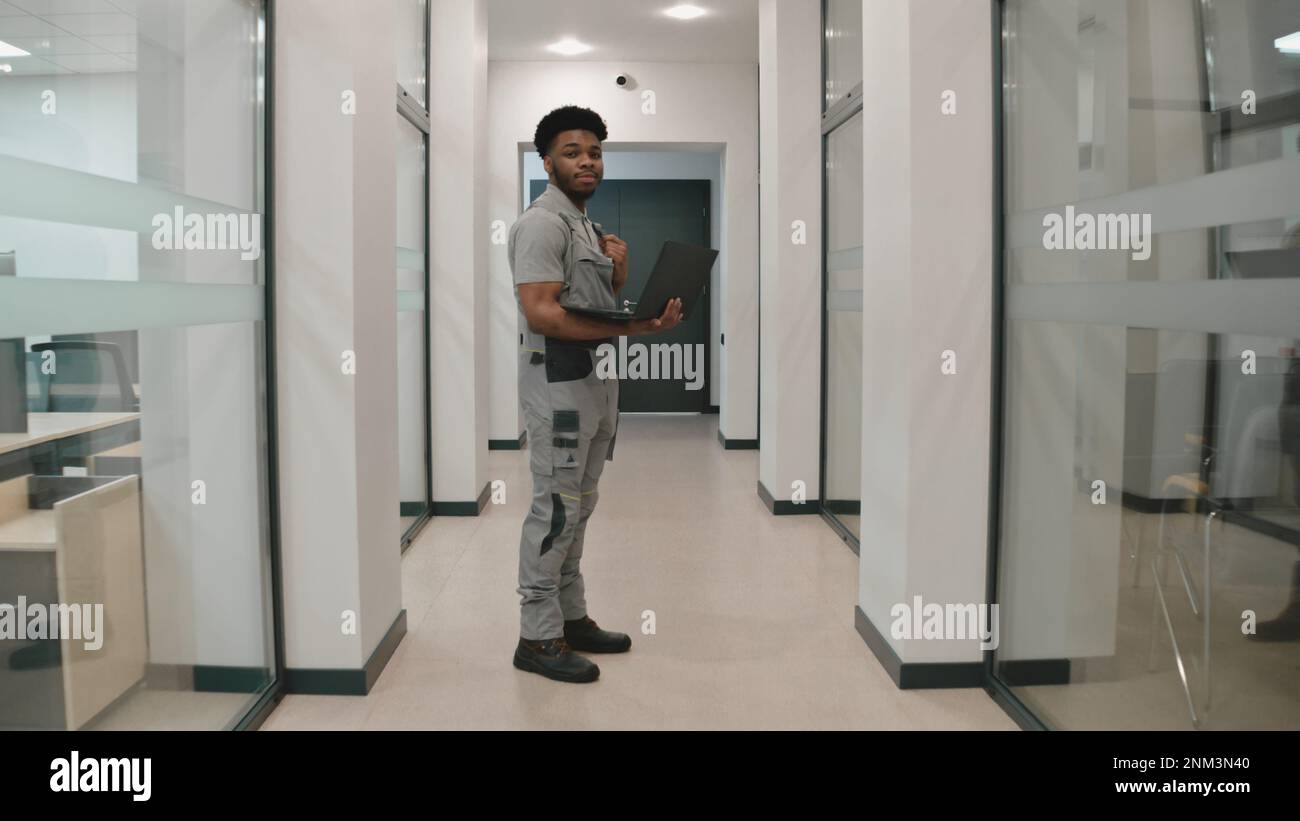 African-American security cameras installer in uniform stands in ...