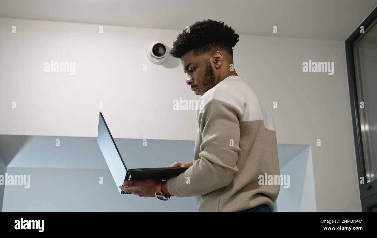 African american man sets up security cameras in office corridor using ...