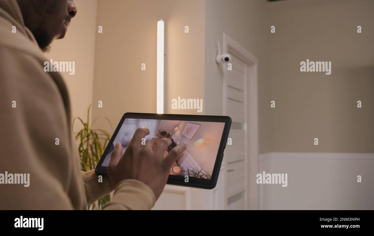 African American man checks security camera after installation. He sets ...