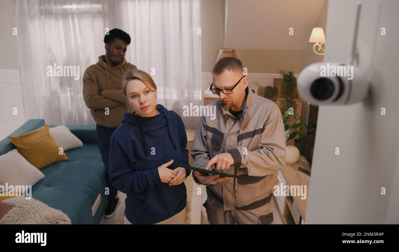 Installer sets up security camera at home of multi ethnic family using ...