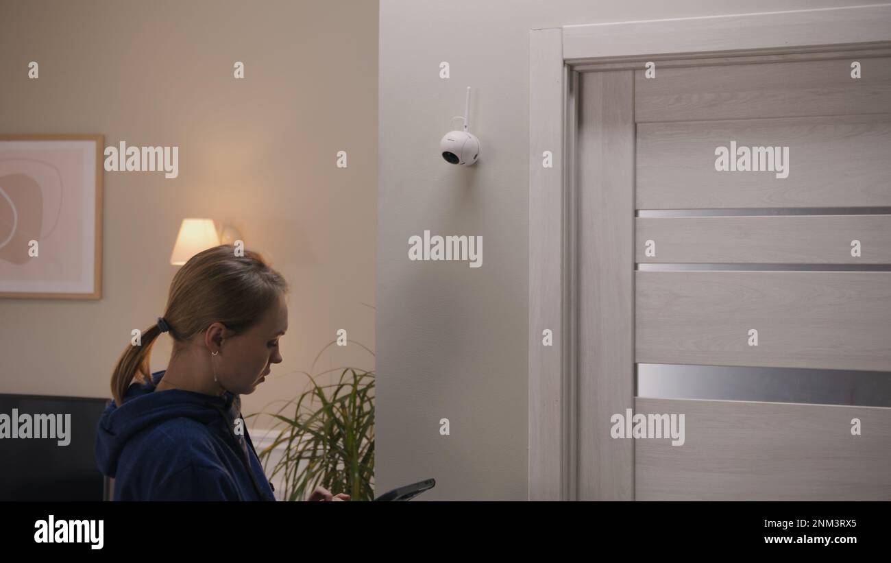 Caucasian woman completes installation of security camera. Woman sets ...