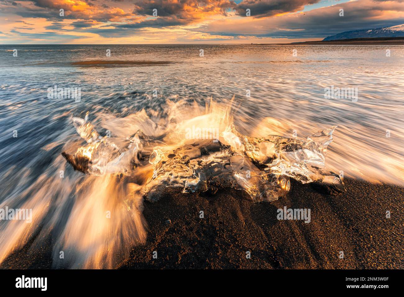 Wave crashing iceberg melting on black sand beach in the sunset at ...