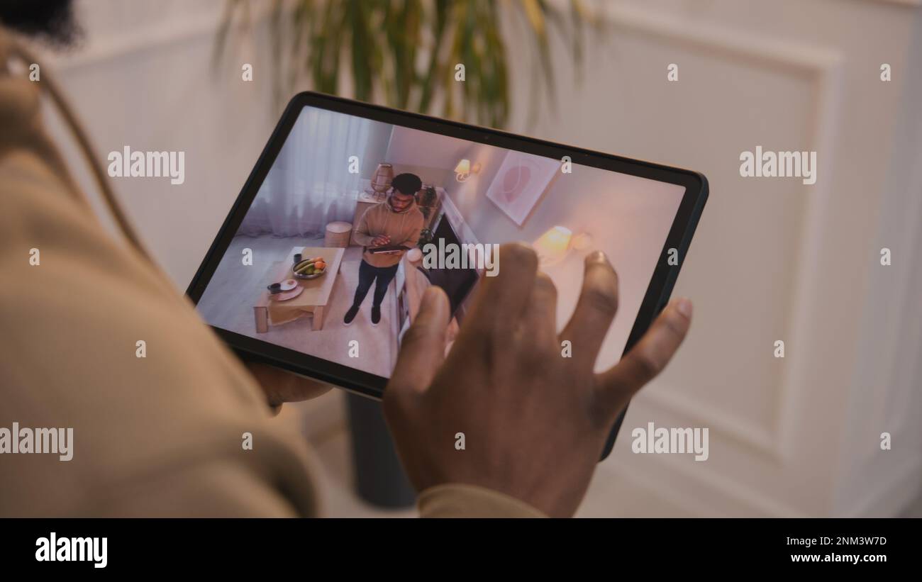African American man checks security camera after installation. He sets ...
