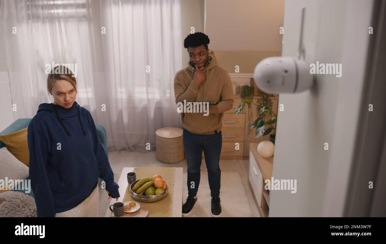 Multi ethnic couple install and set up security camera. Woman moves to ...