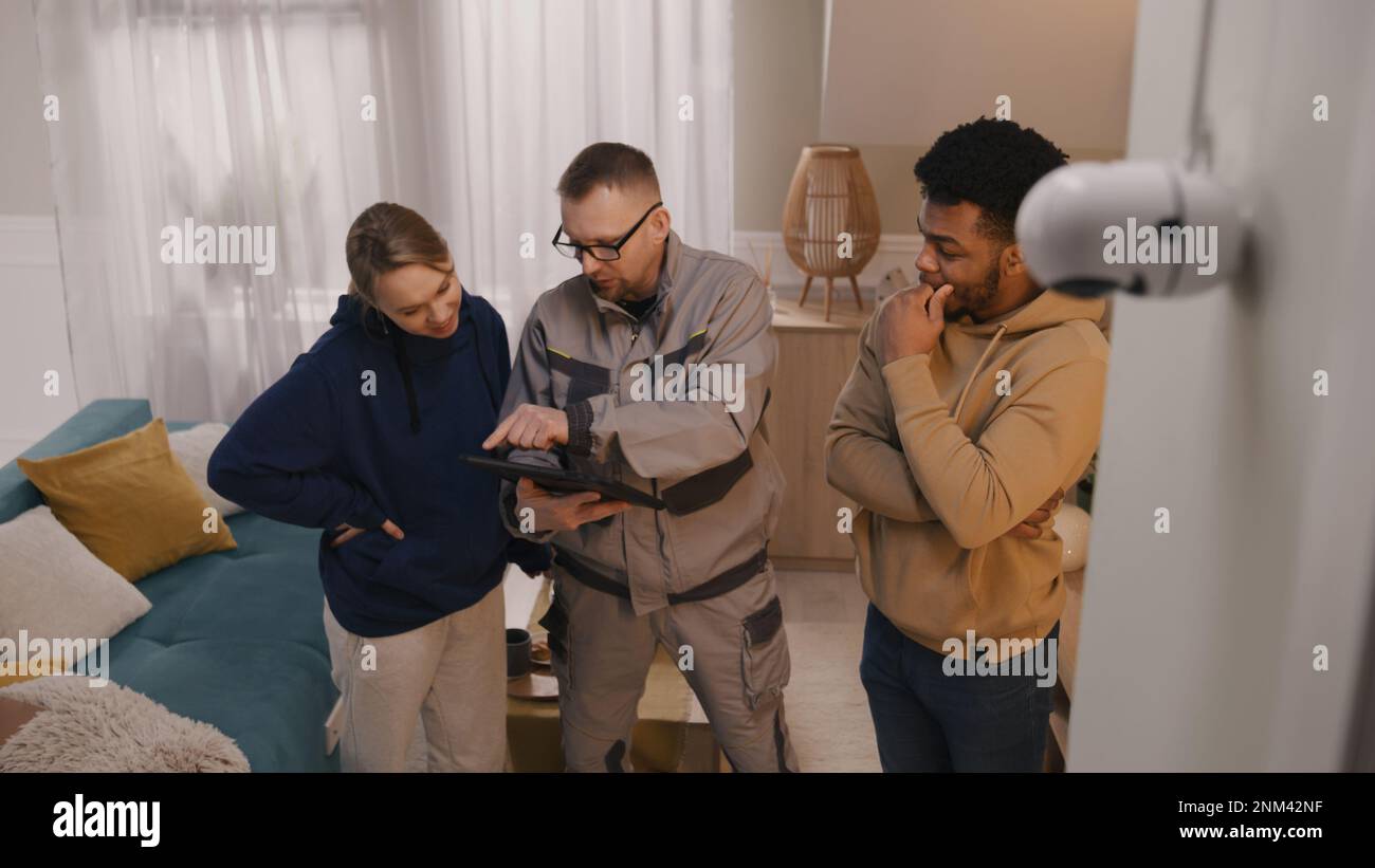 Installer sets up security camera in apartment using digital tablet ...