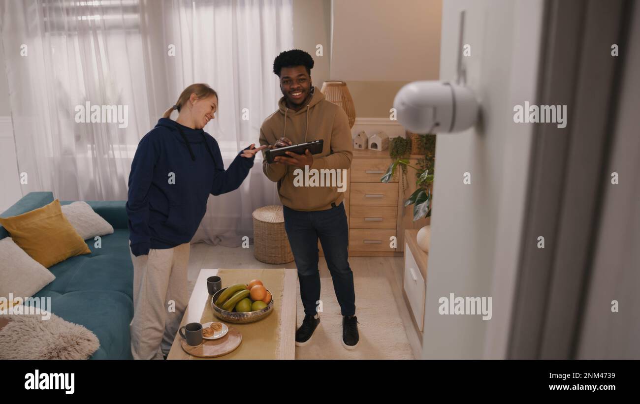 Multi ethnic couple install and set up security camera. Woman moves to ...