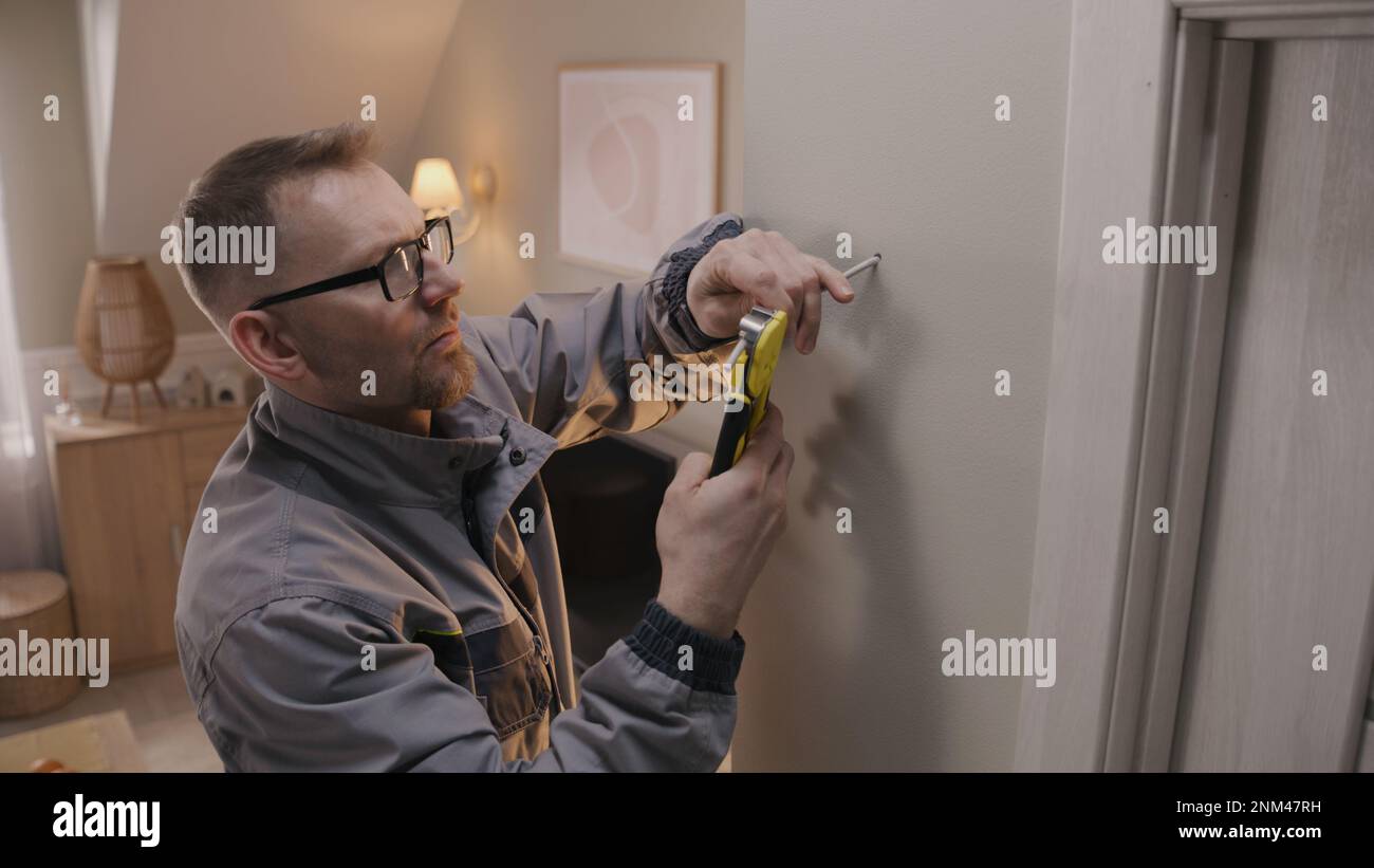 Man in uniform puts cable in drilled hole. Electrician removes ...