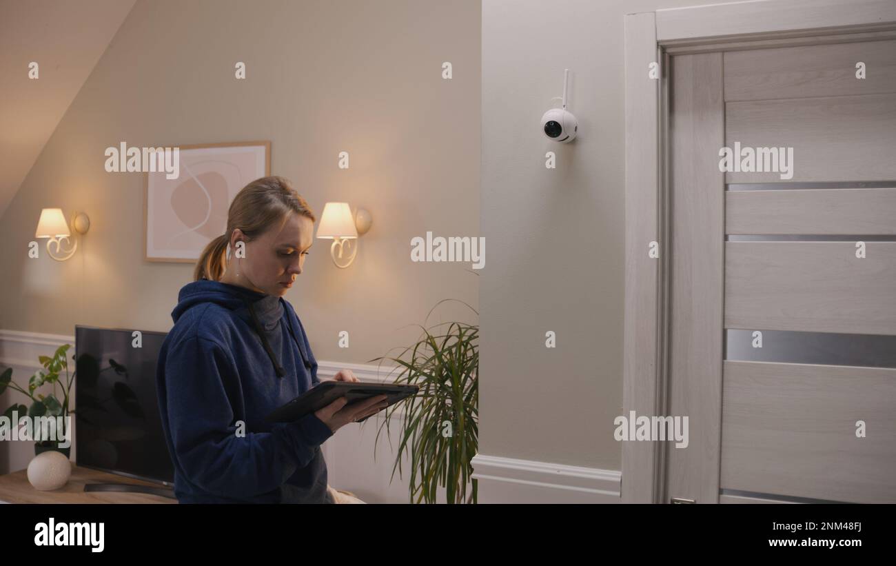 Caucasian woman completes installation of security camera. Woman sets ...
