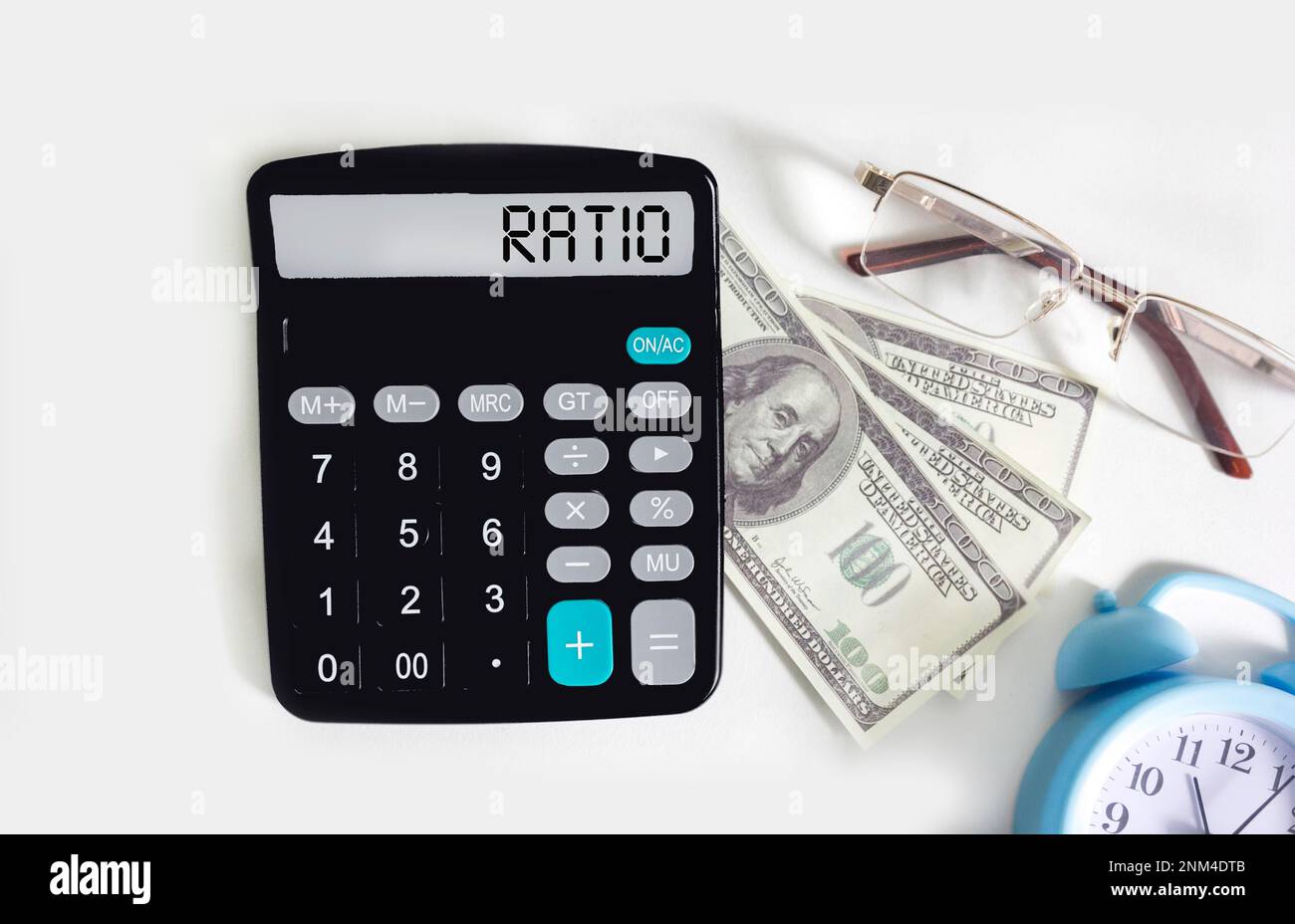 On a white background, dollars and a calculator with the text RATIO ...
