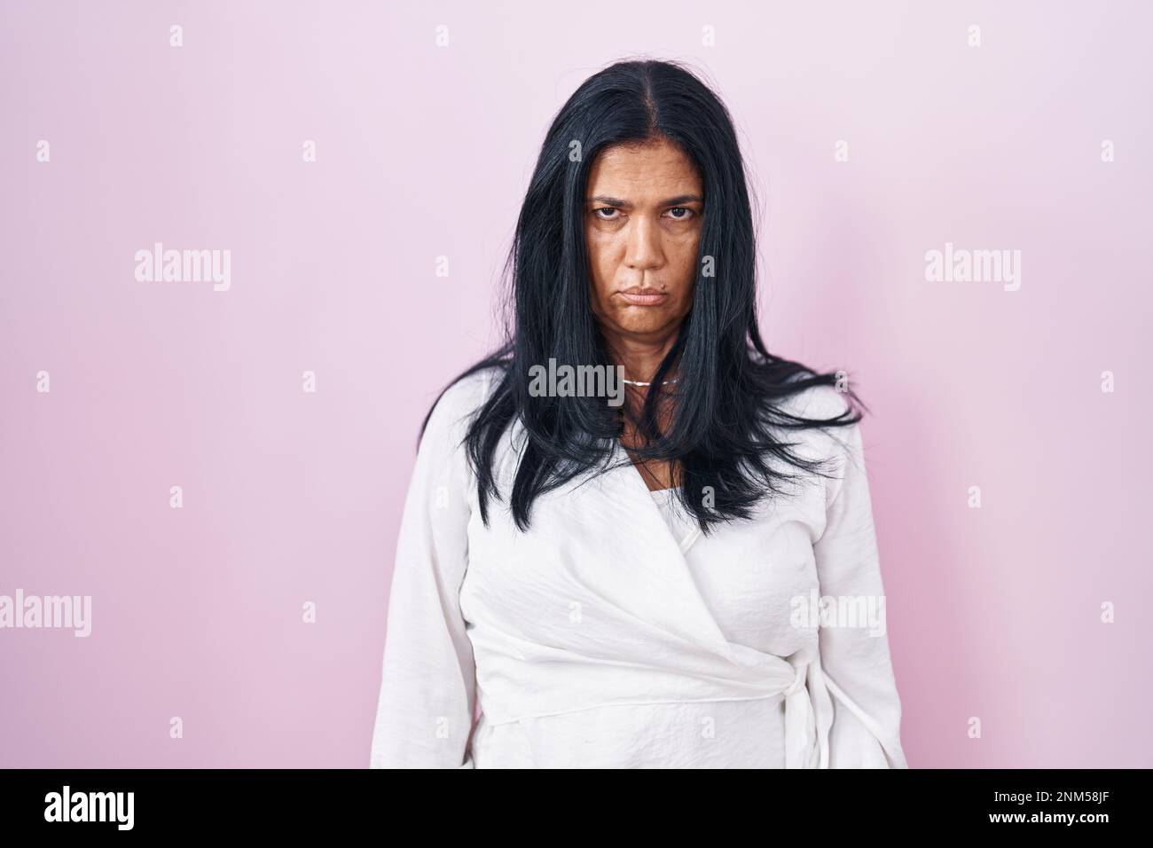 Mature hispanic woman standing over pink background depressed and worry ...