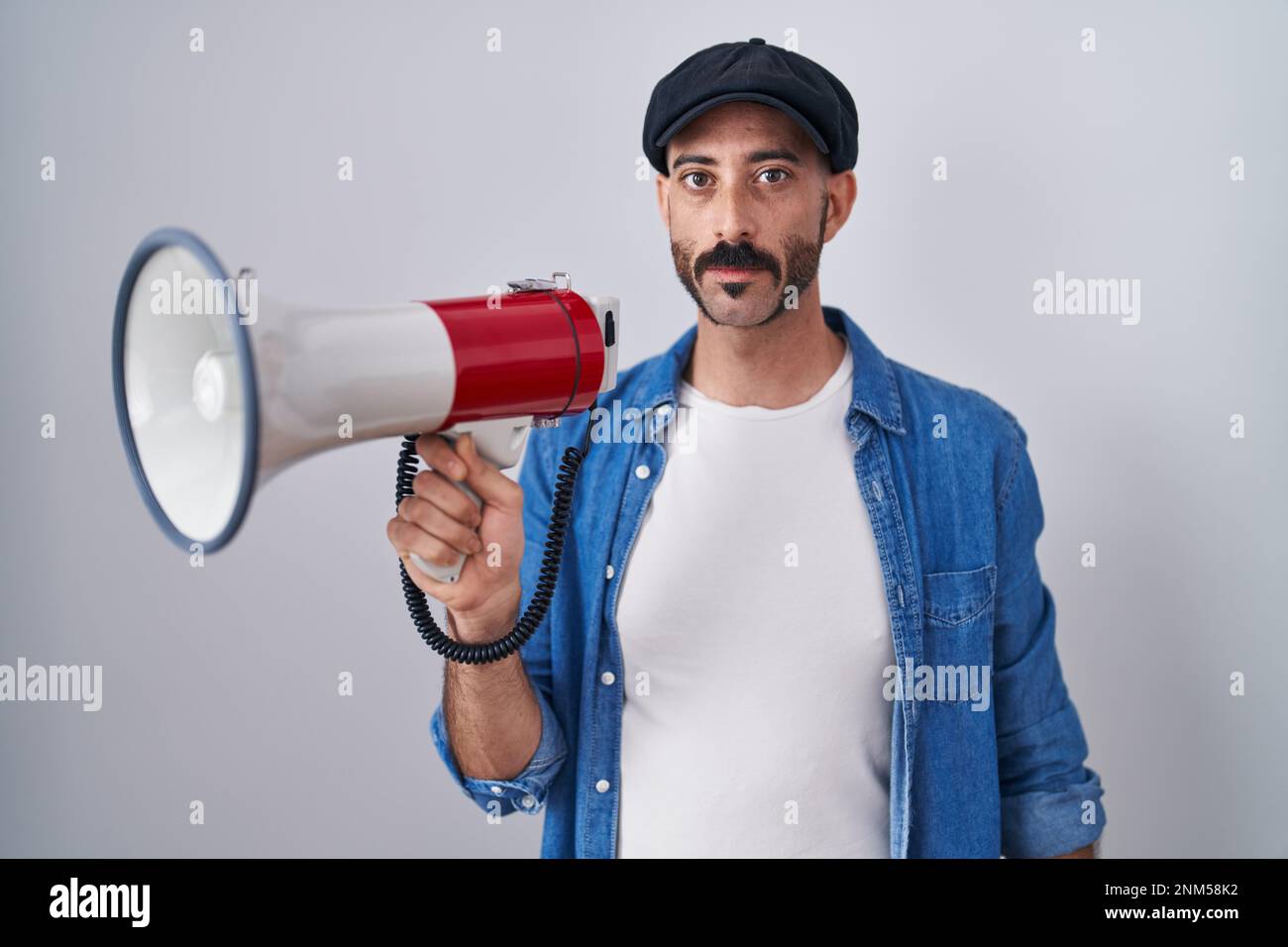 Hispanic man with beard shouting through megaphone thinking attitude ...