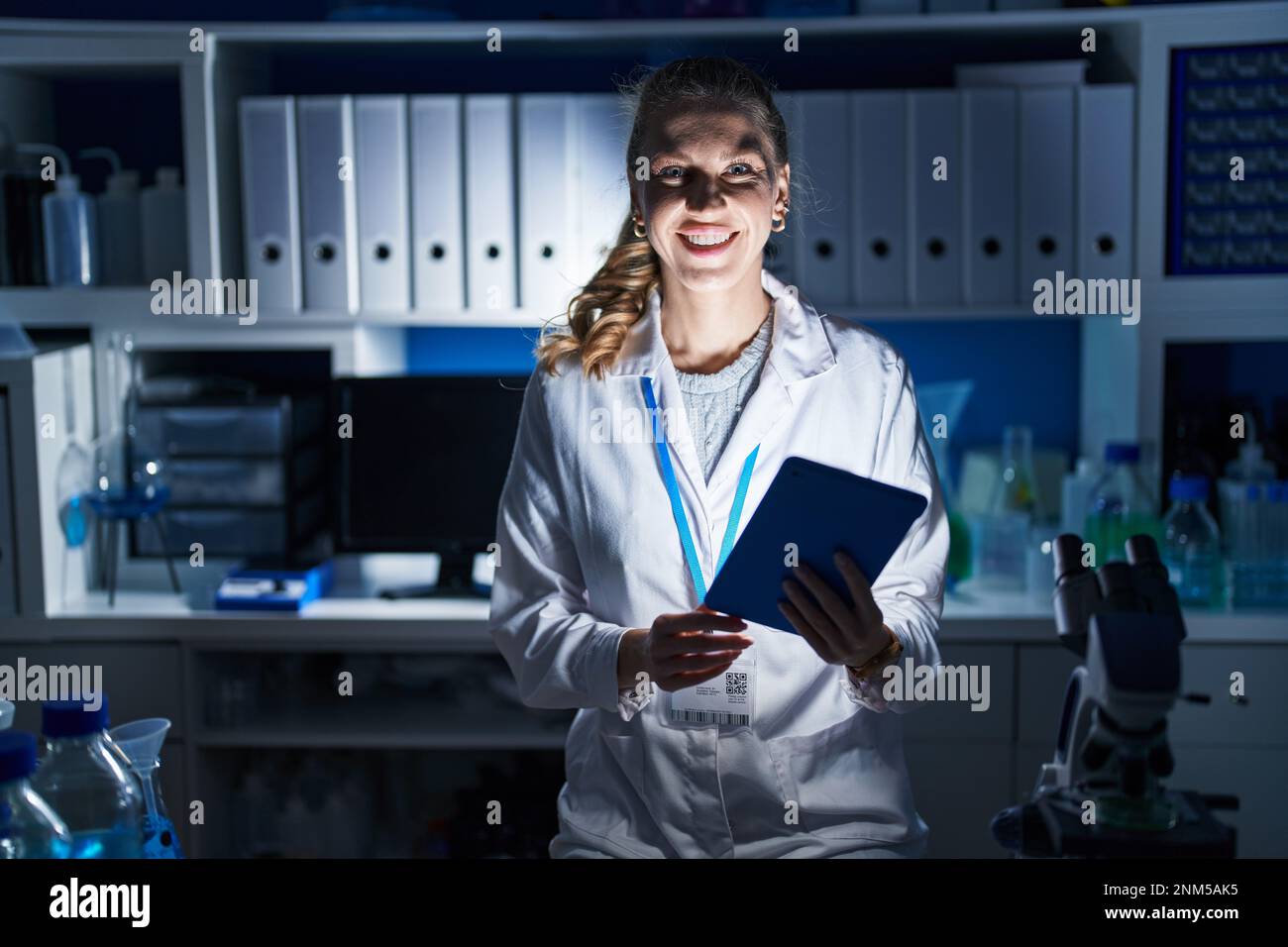 Beautiful blonde woman working at scientist laboratory late at night ...