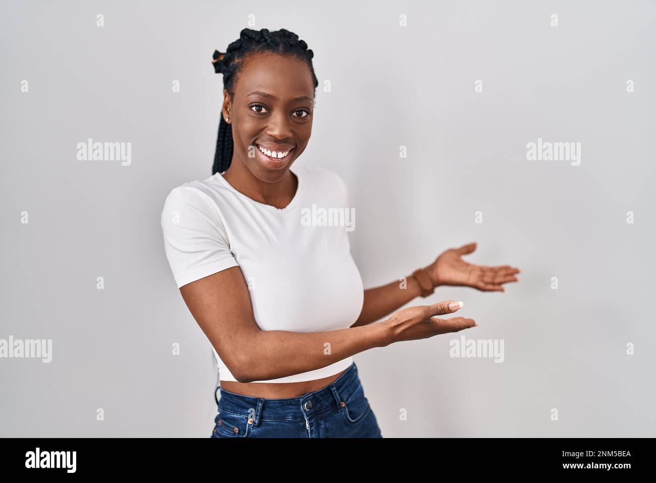 Beautiful black woman standing over isolated background inviting to ...
