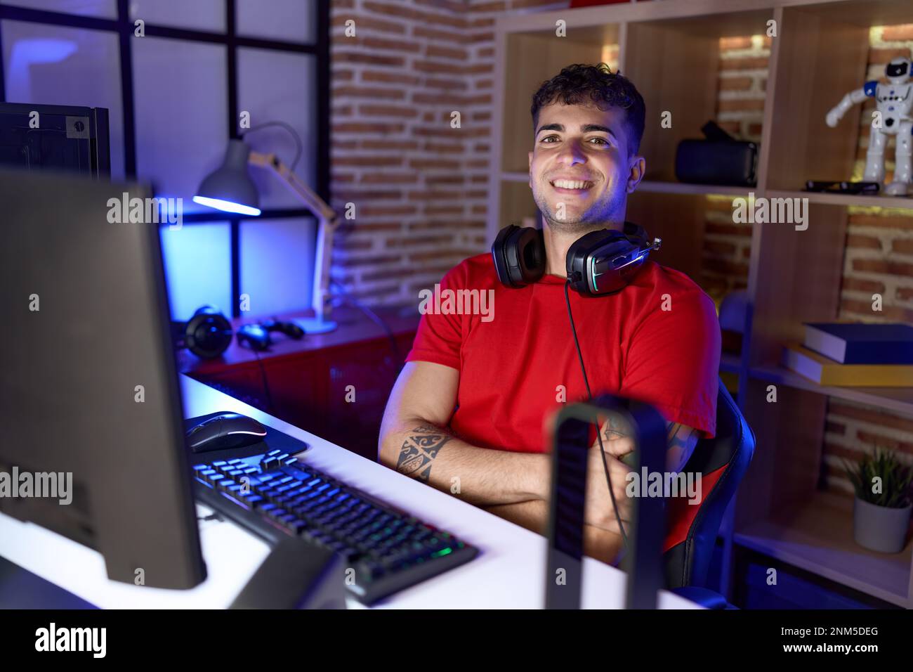 Young hispanic man streamer smiling confident sitting with arms crossed ...