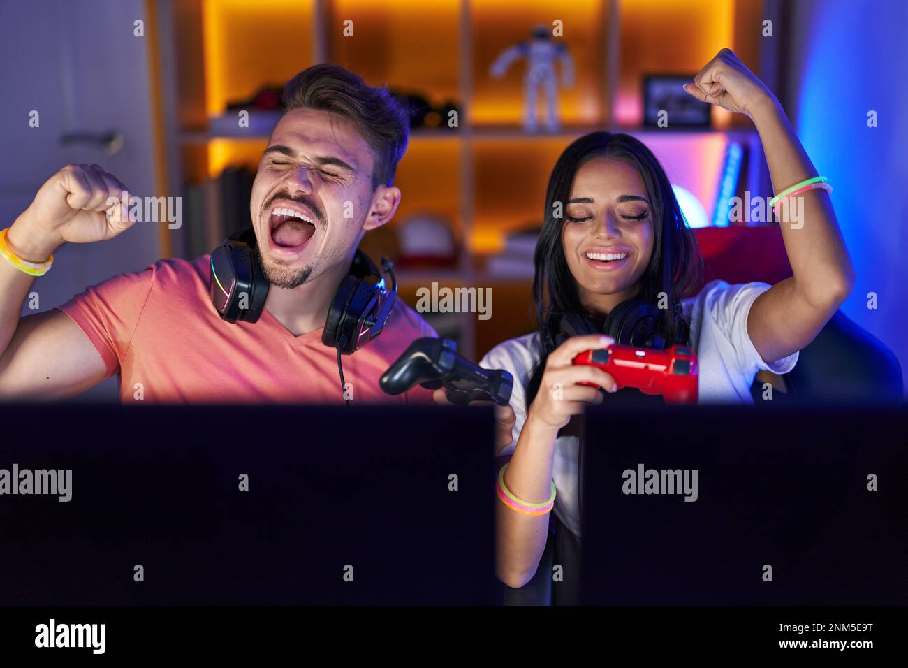 Man and woman streamers playing video game using computer and joystick ...