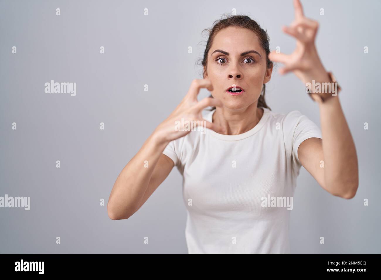 Beautiful brunette woman standing over isolated background shouting ...