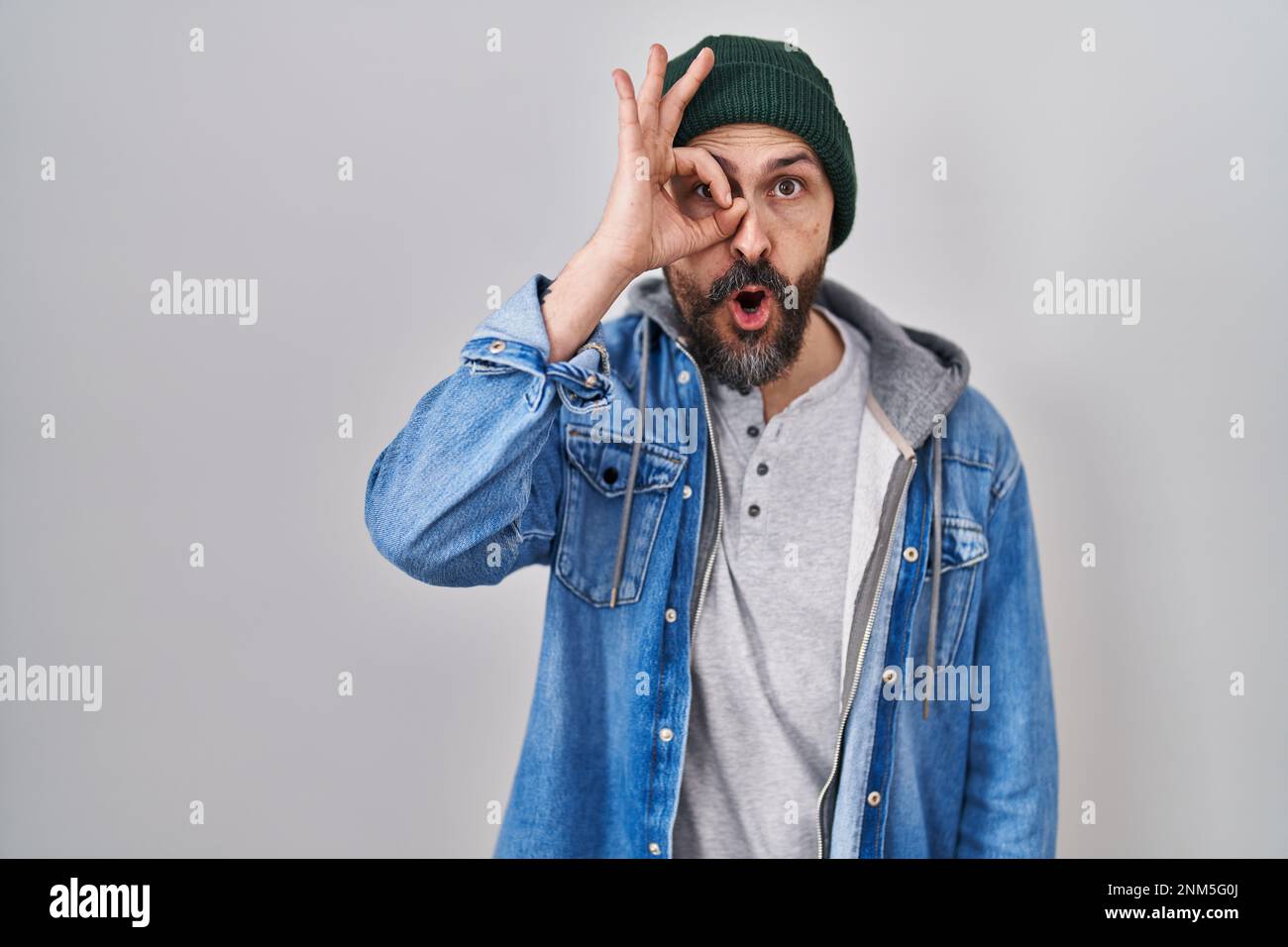 Young hispanic man with tattoos wearing wool cap doing ok gesture ...