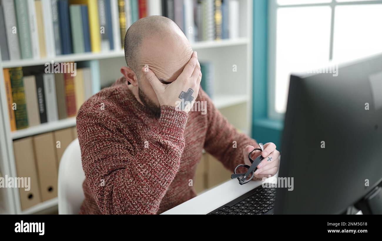 Young bald man student using computer stressed at university classroom ...