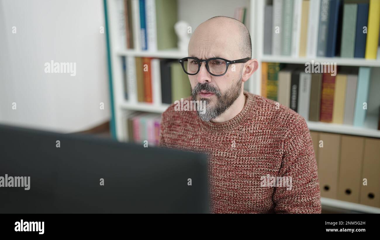 Young bald man student using computer studying at university classroom ...