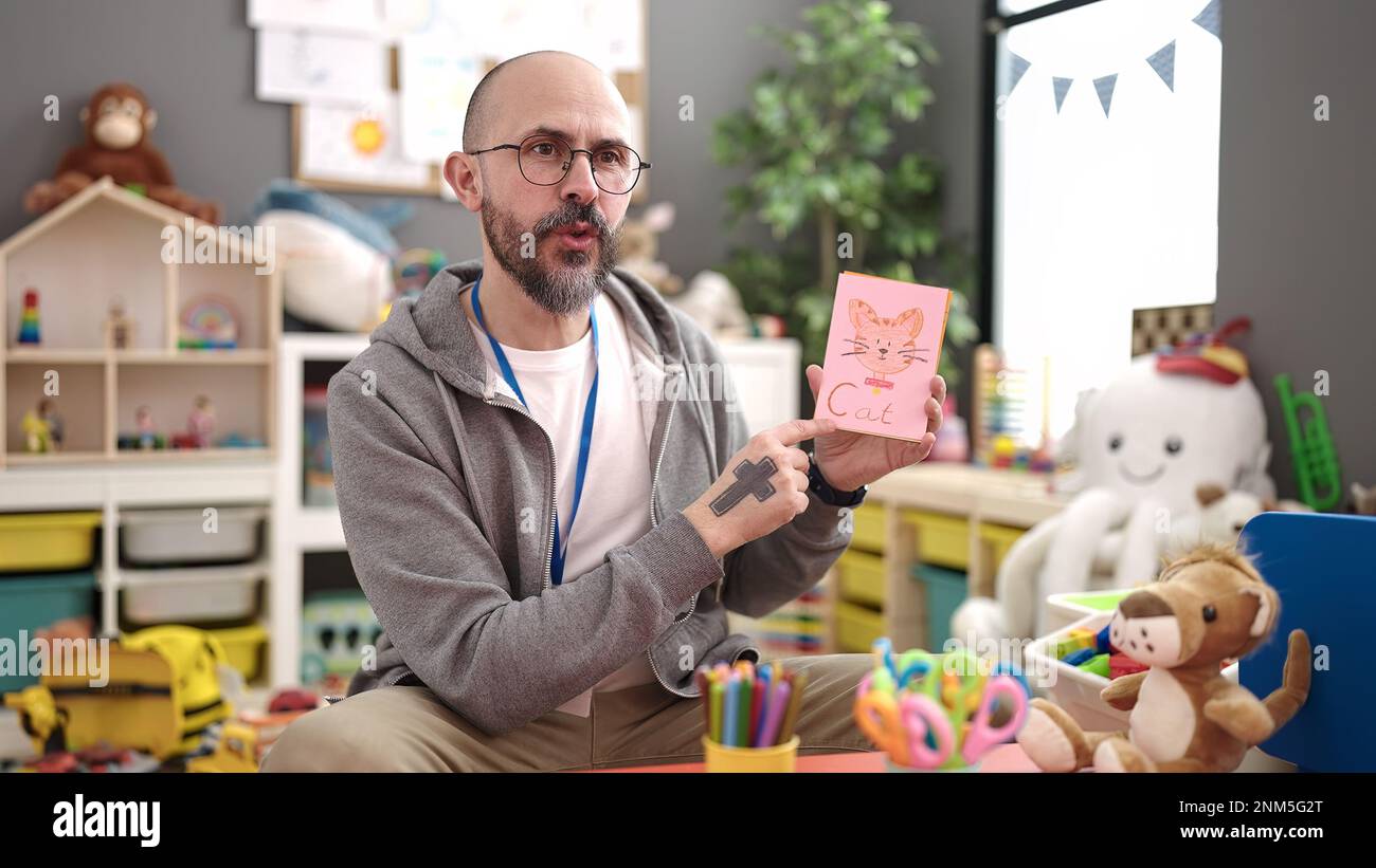 Young bald man preschool teacher teaching vocabulary lesson at ...