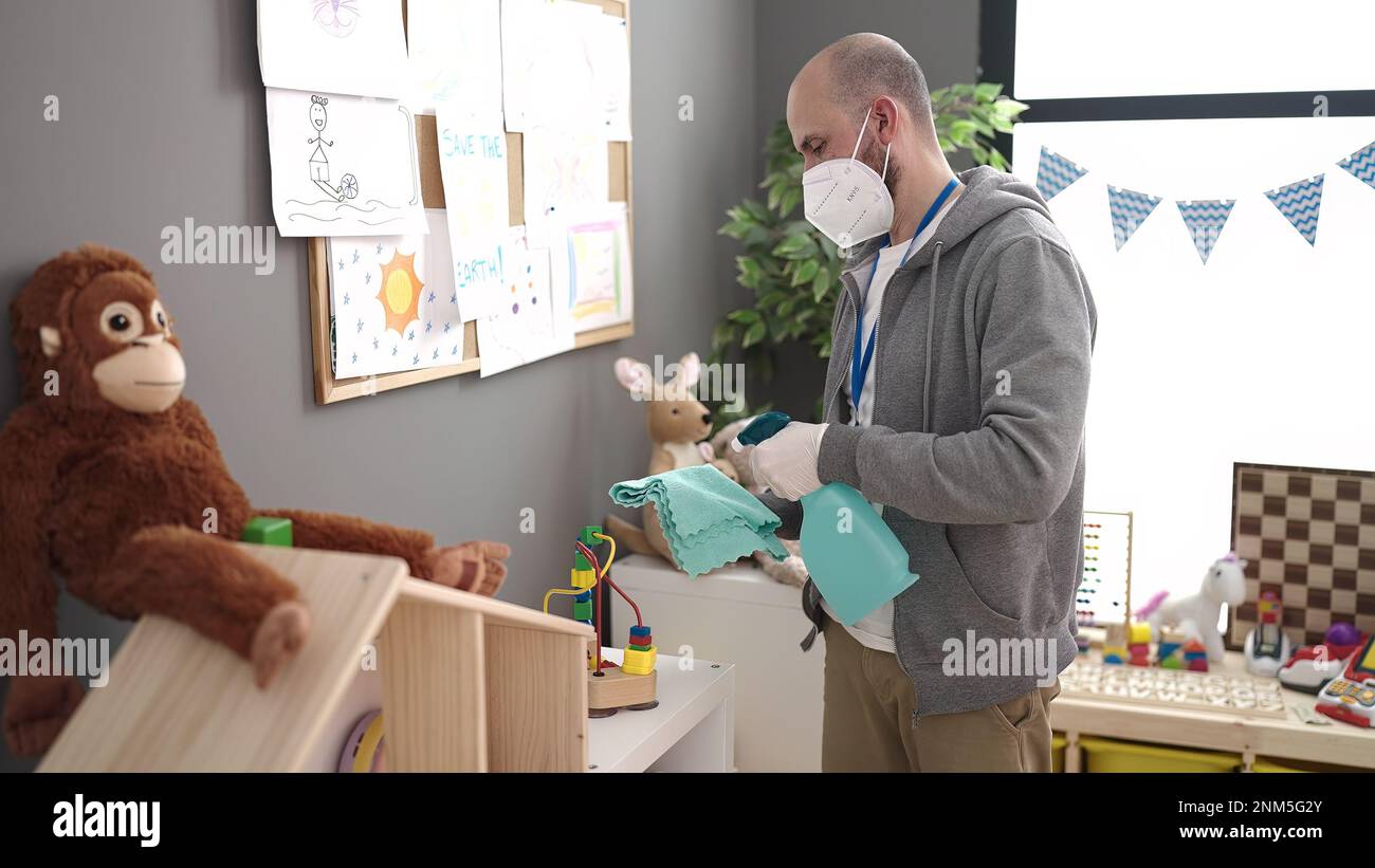 Young bald man preschool teacher wearing medical mask cleaning at ...