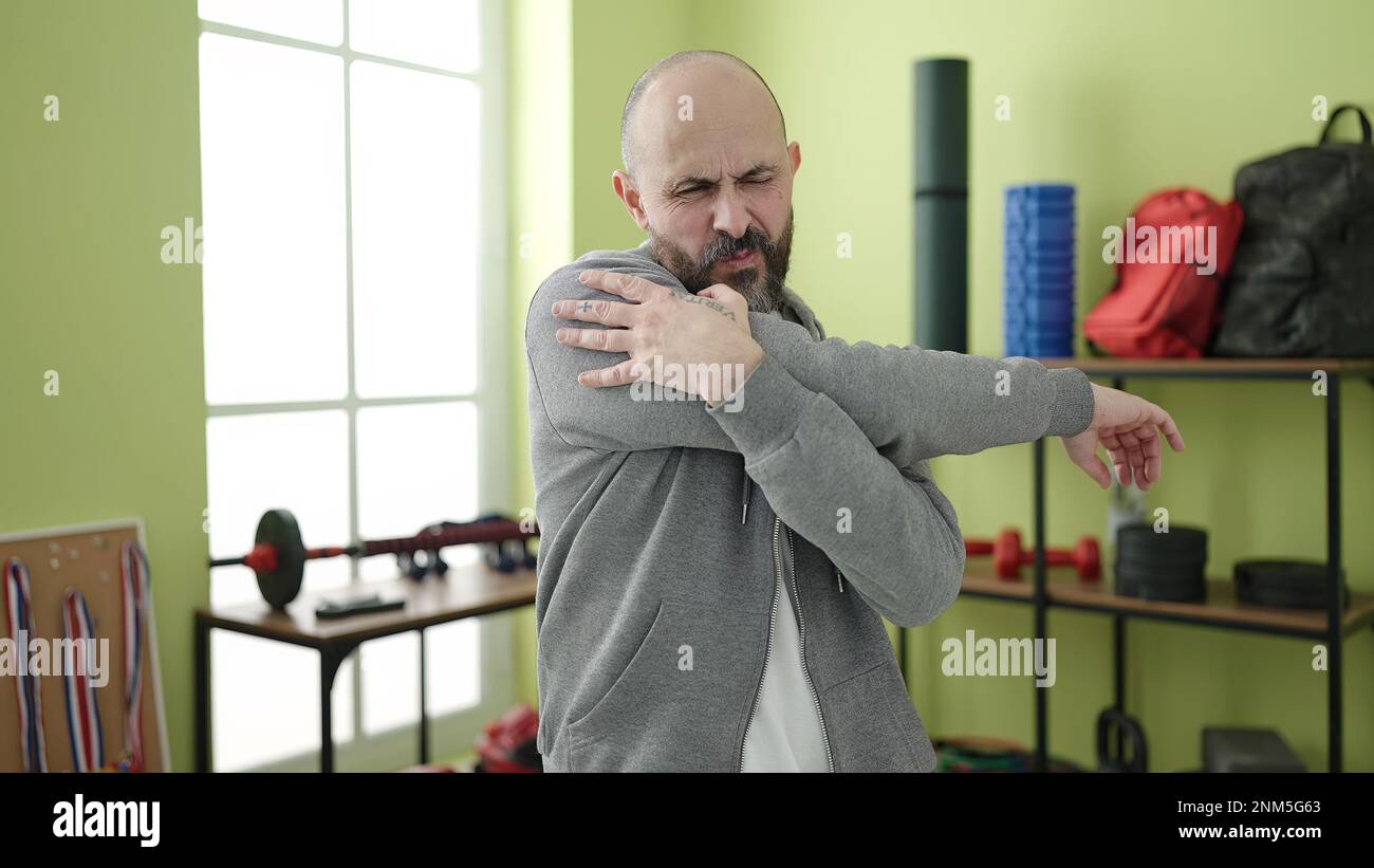 Young bald man stretching arm at sport center Stock Photo - Alamy