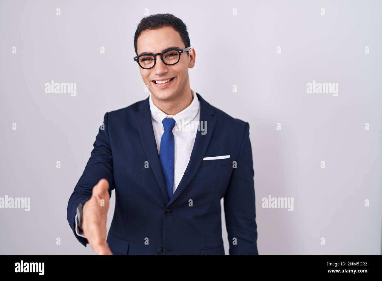 Young hispanic man wearing suit and tie smiling friendly offering ...
