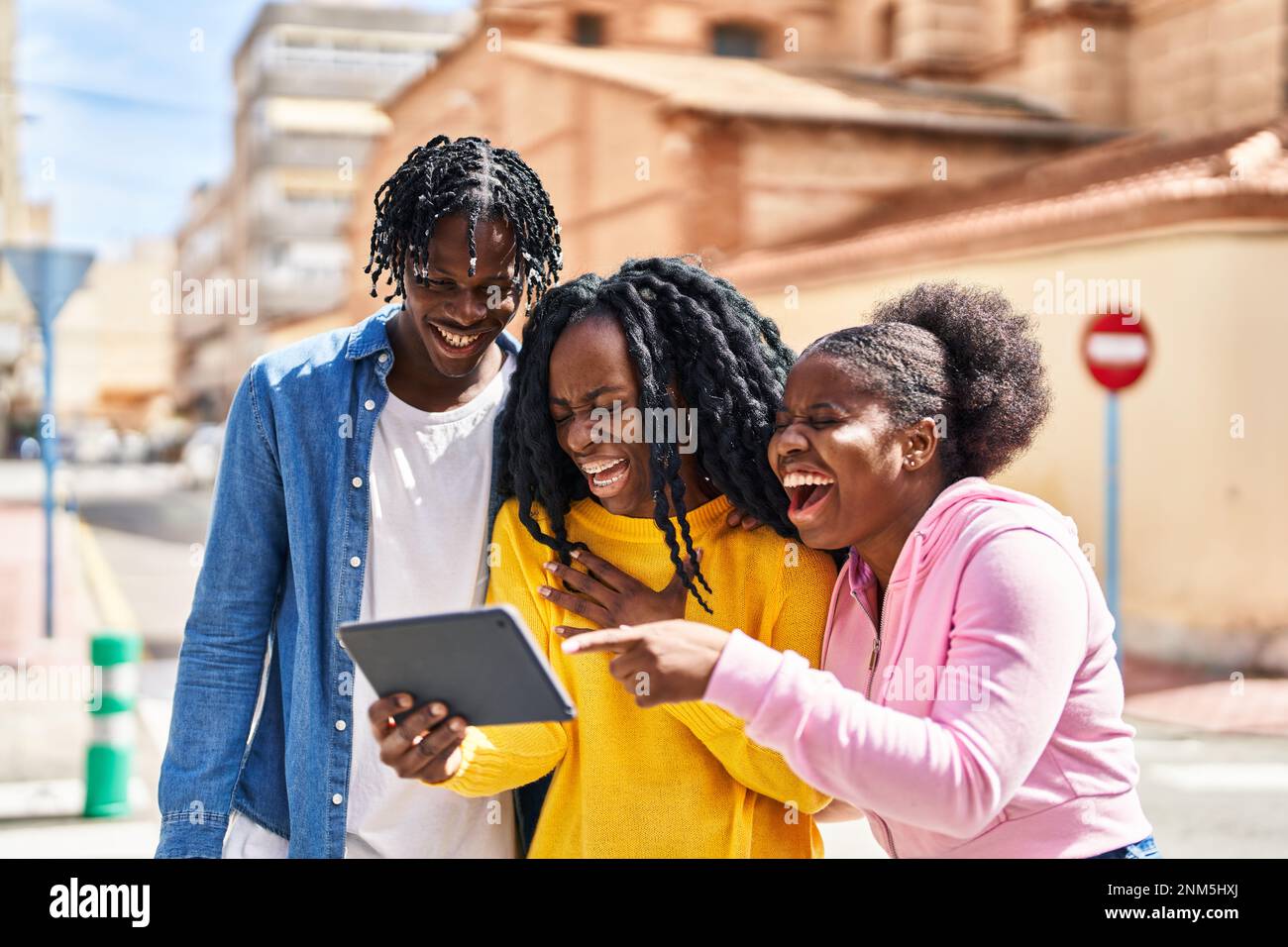 African american friends standing together watching video on touchpad ...