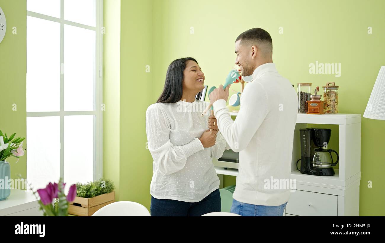 Man and woman couple singing song using cook utensil as a microphone at ...