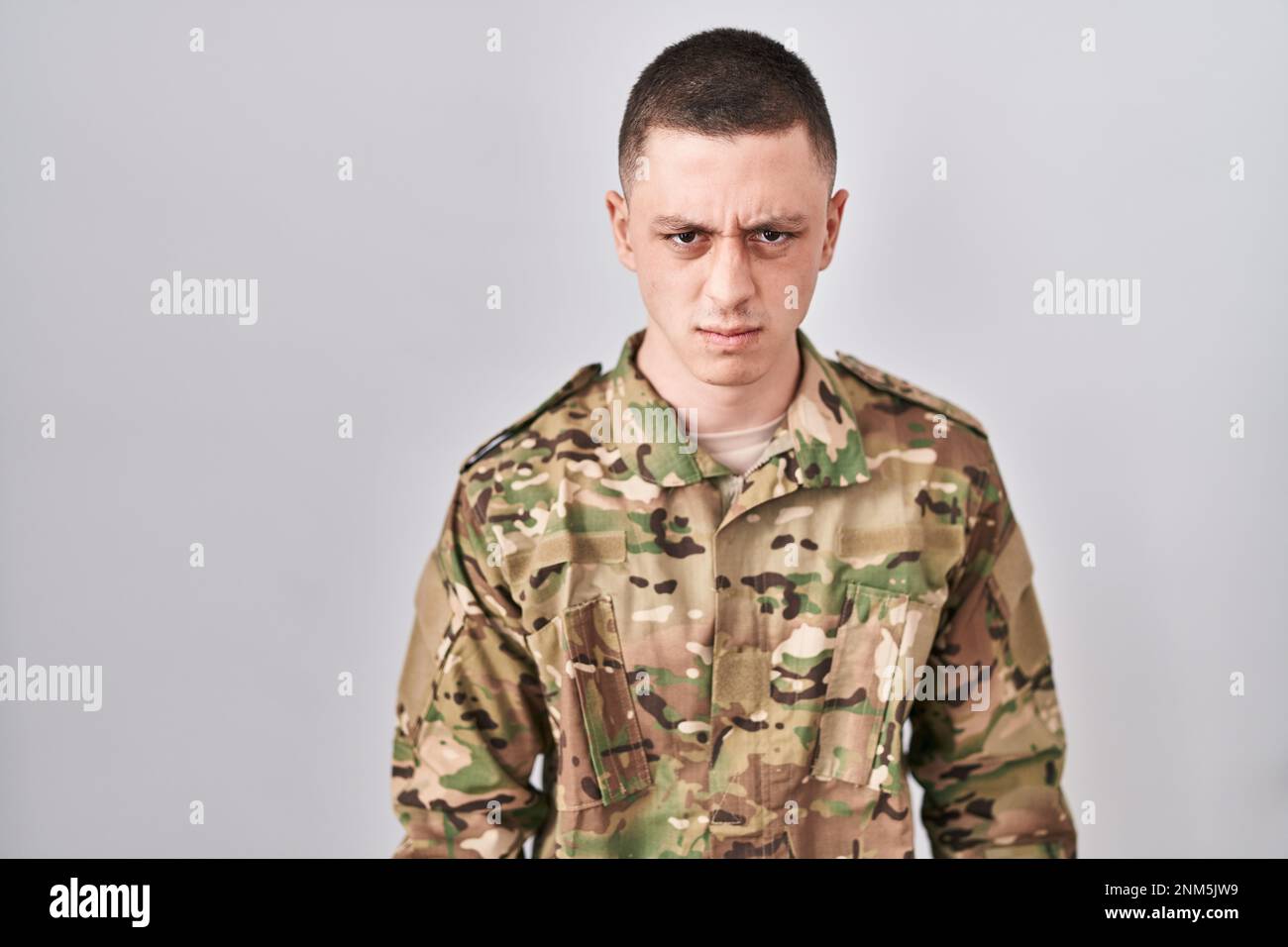 Young man wearing camouflage army uniform skeptic and nervous, frowning ...