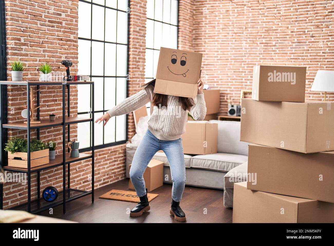 Young woman dancing with funny cardboard box on head at new home Stock ...