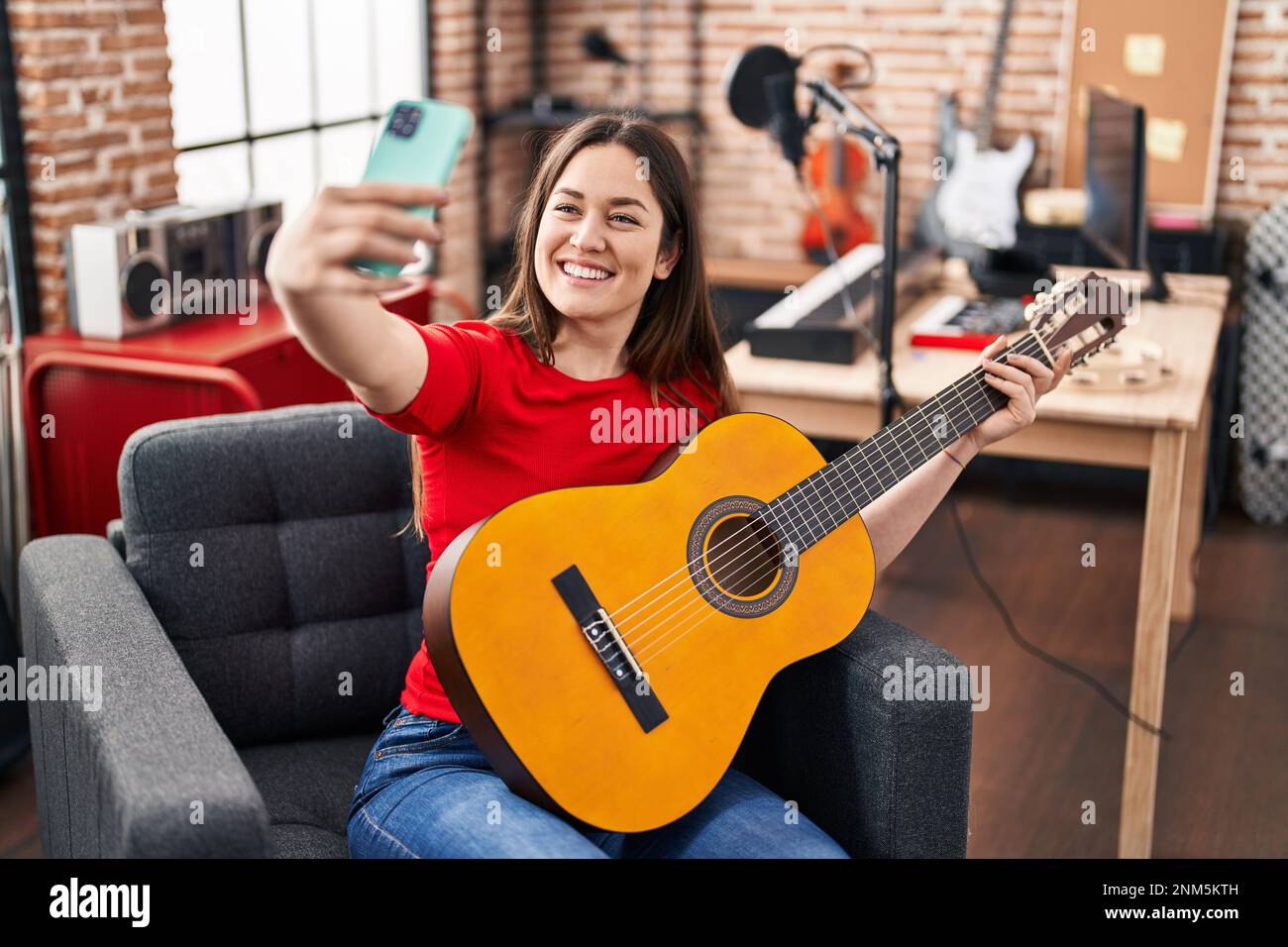 Young woman musician make selfie by smartphone playing classical guitar ...