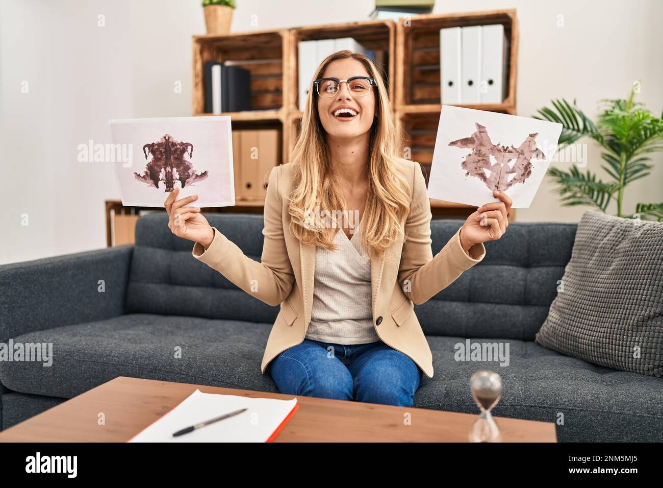 Young blonde therapist woman holding rorschach test smiling and ...
