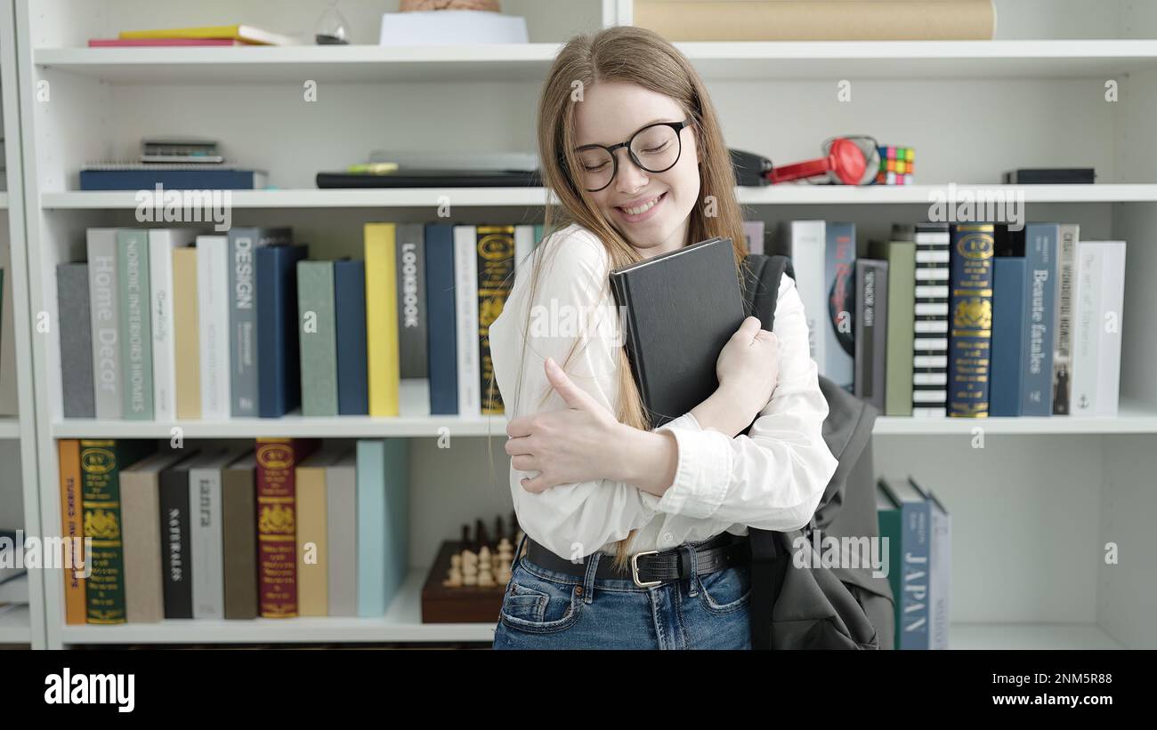 Young blonde woman student standing hugging book at university ...