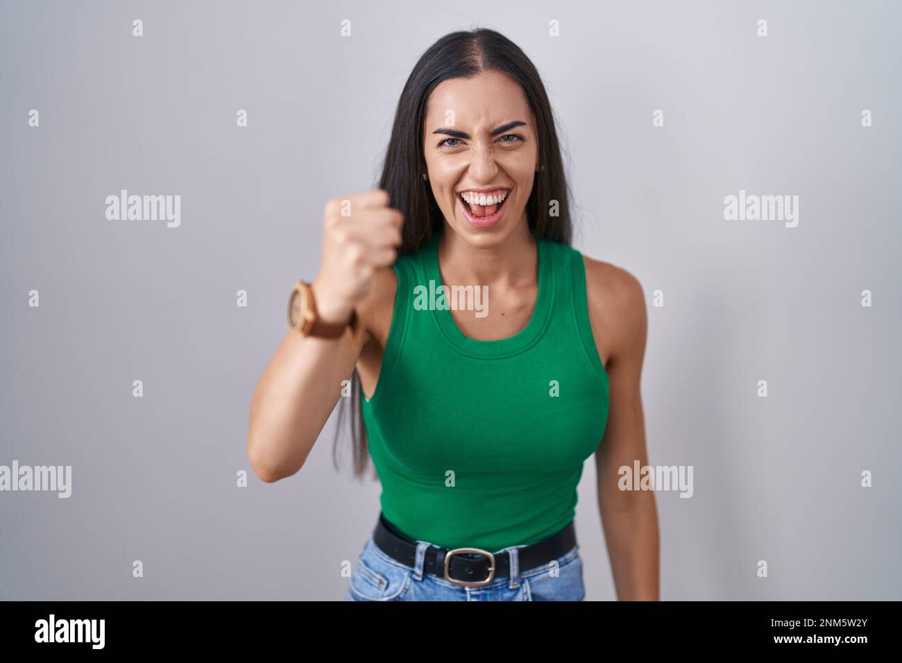 Young woman standing over isolated background angry and mad raising ...