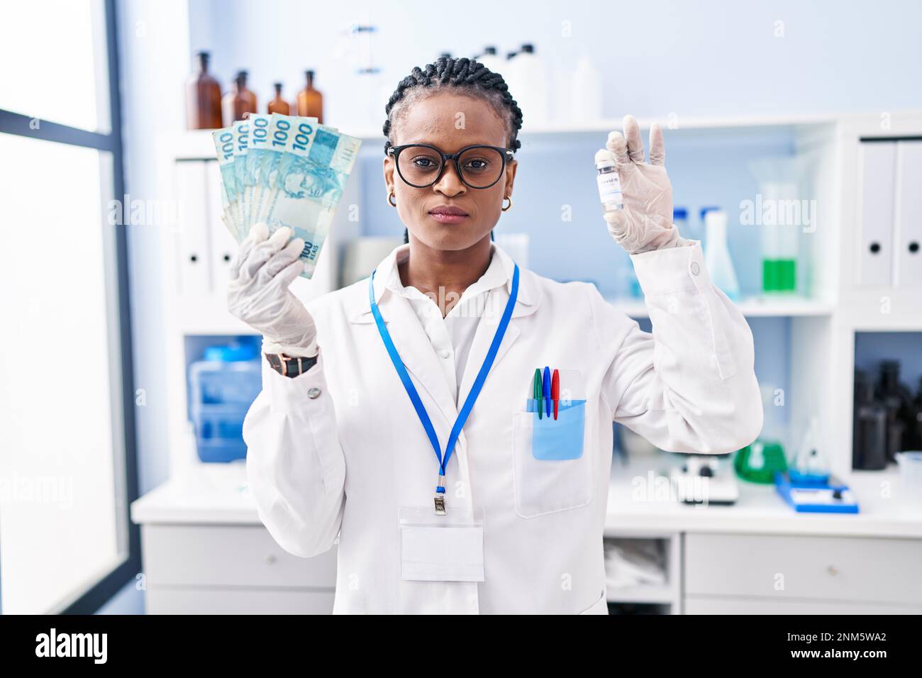 African woman with braids working at scientist laboratory holding money ...