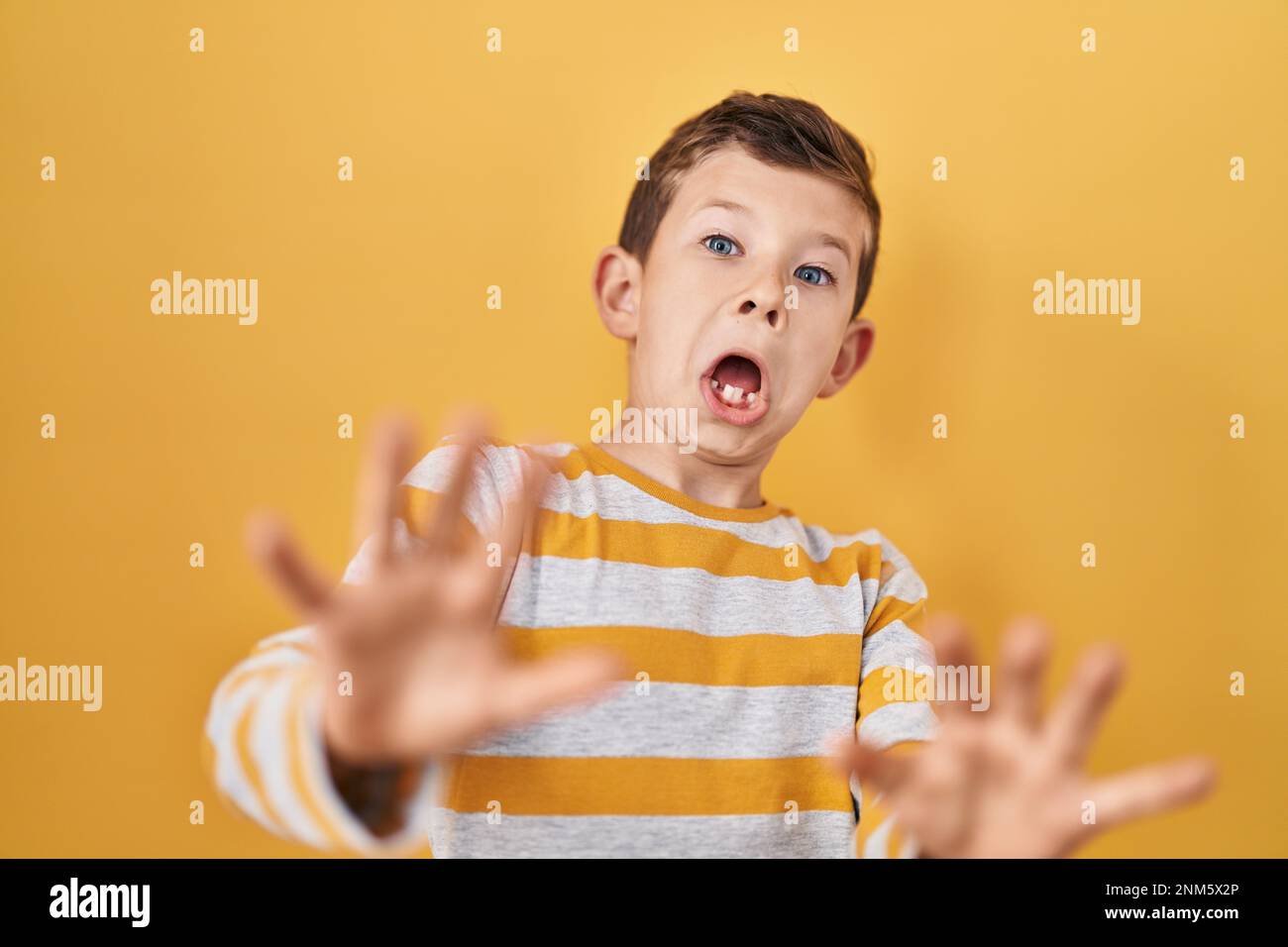 Young caucasian kid standing over yellow background afraid and ...