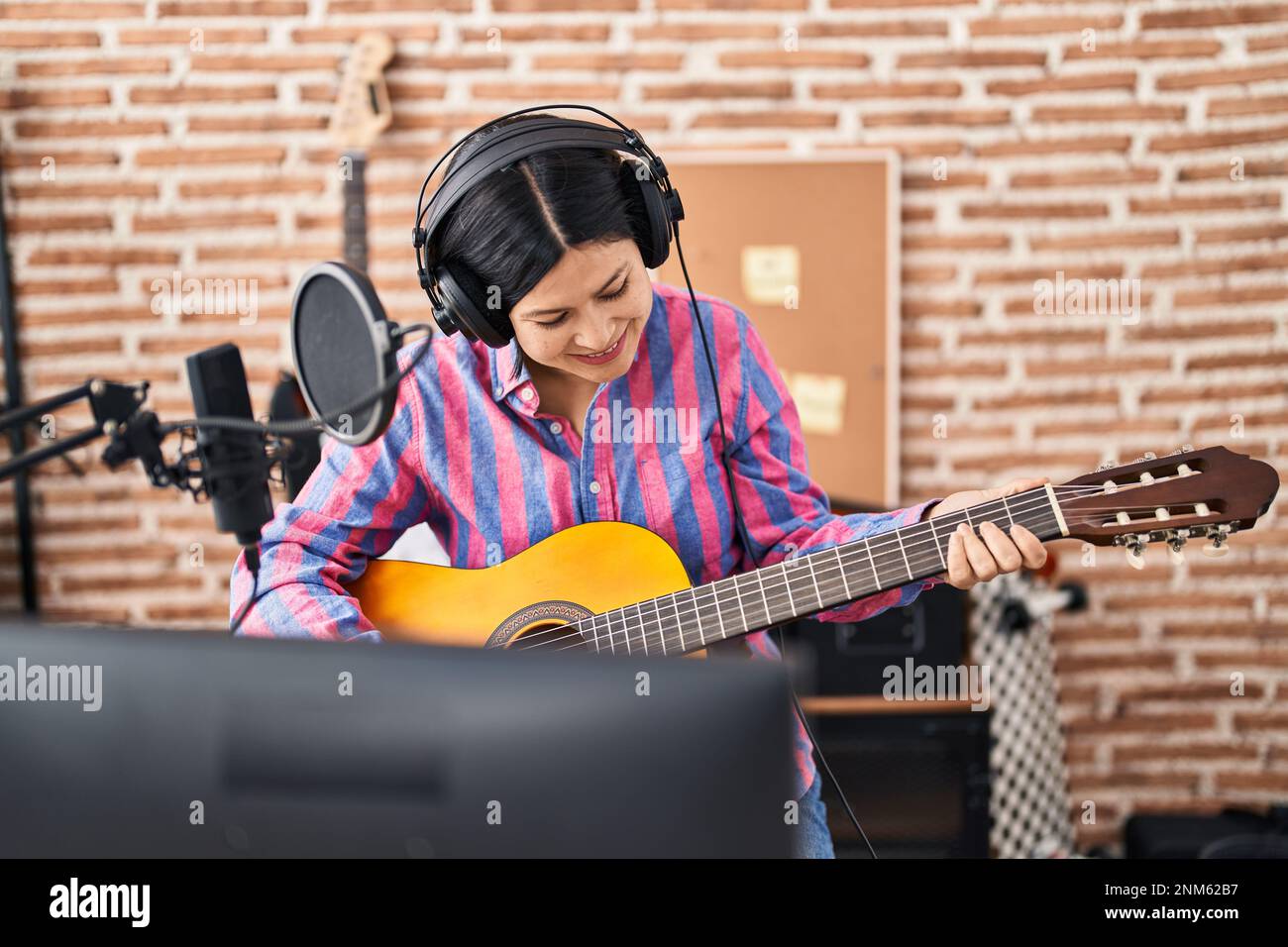 Young chinese woman musician playing guitar at music studio Stock Photo ...