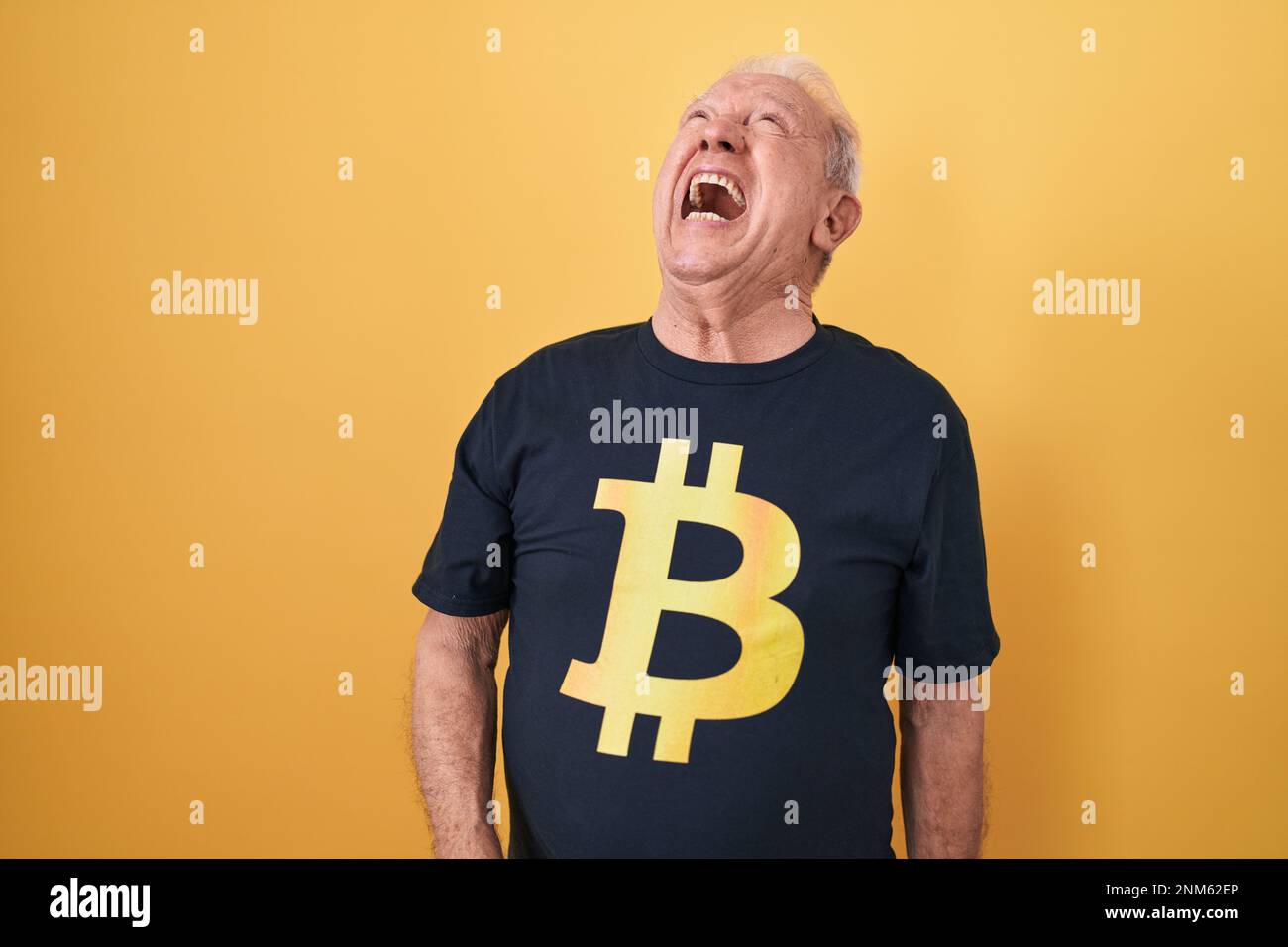 Senior man with grey hair wearing bitcoin t shirt angry and mad ...