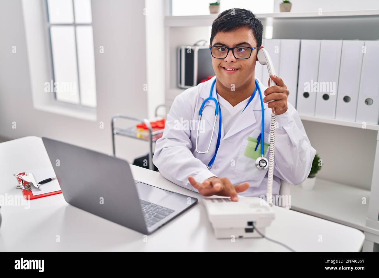 Down syndrome man wearing doctor uniform talking on the telephone at ...