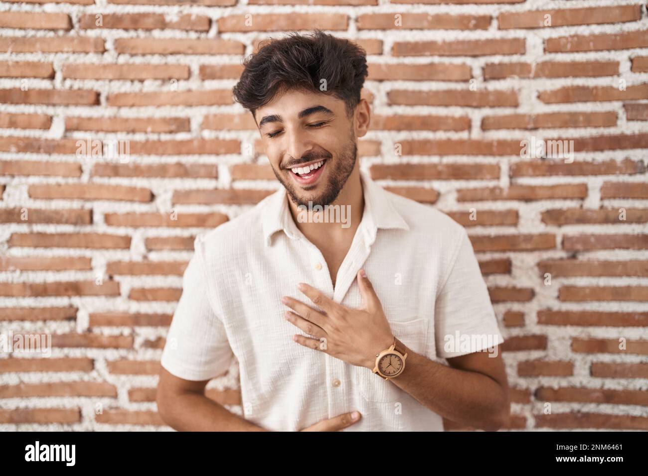 Arab man with beard standing over bricks wall background smiling and ...